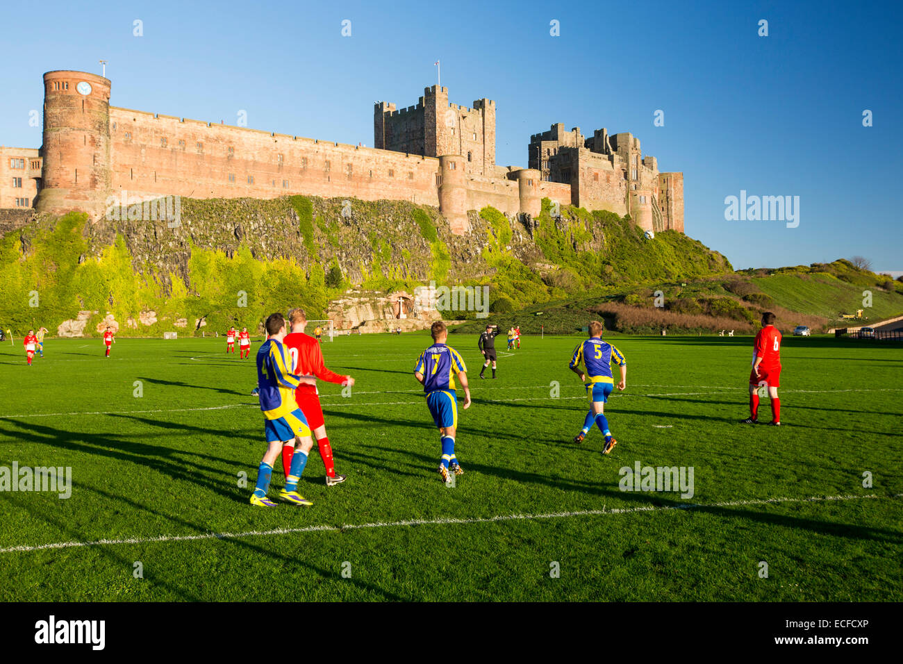 A team palying football infront of Bamburgh Castle, Northumberland, UK ...