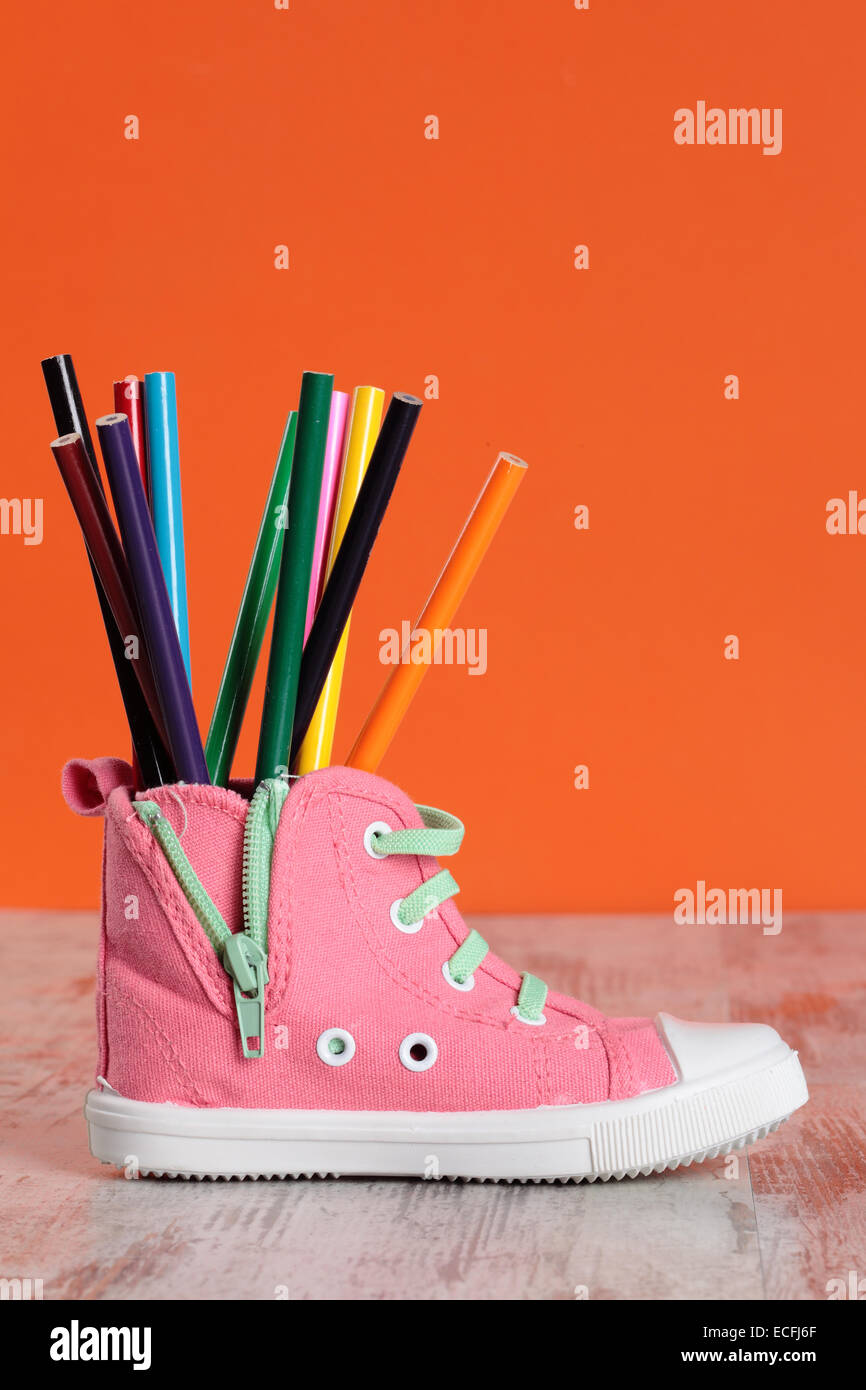 child shoe with colored pencils on an orange background Stock Photo - Alamy