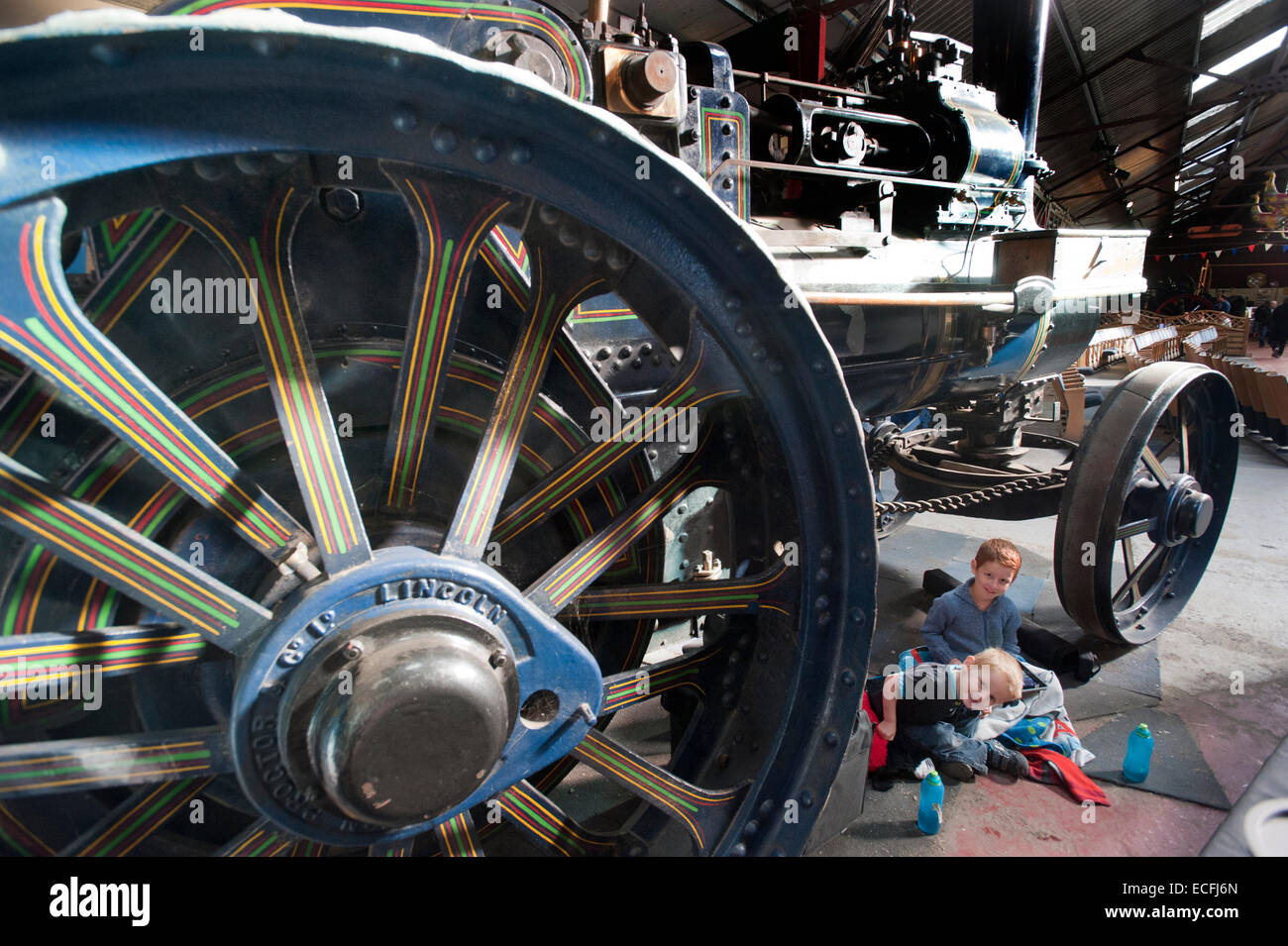 Two young brothers sit under the giant decorative wheels of Traction ...
