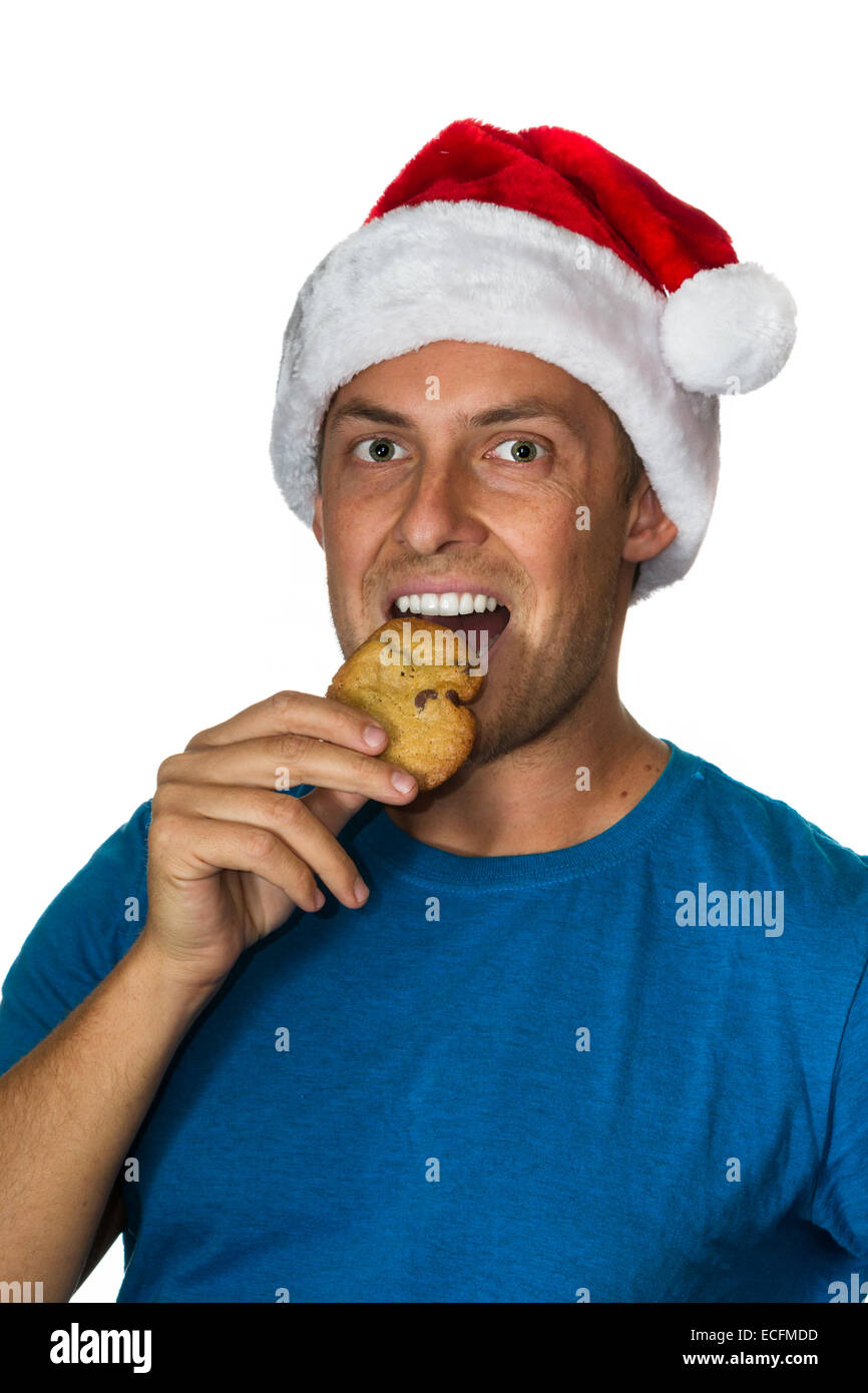 young man eating a chocolate chip cookie wearing a santa hat Stock ...