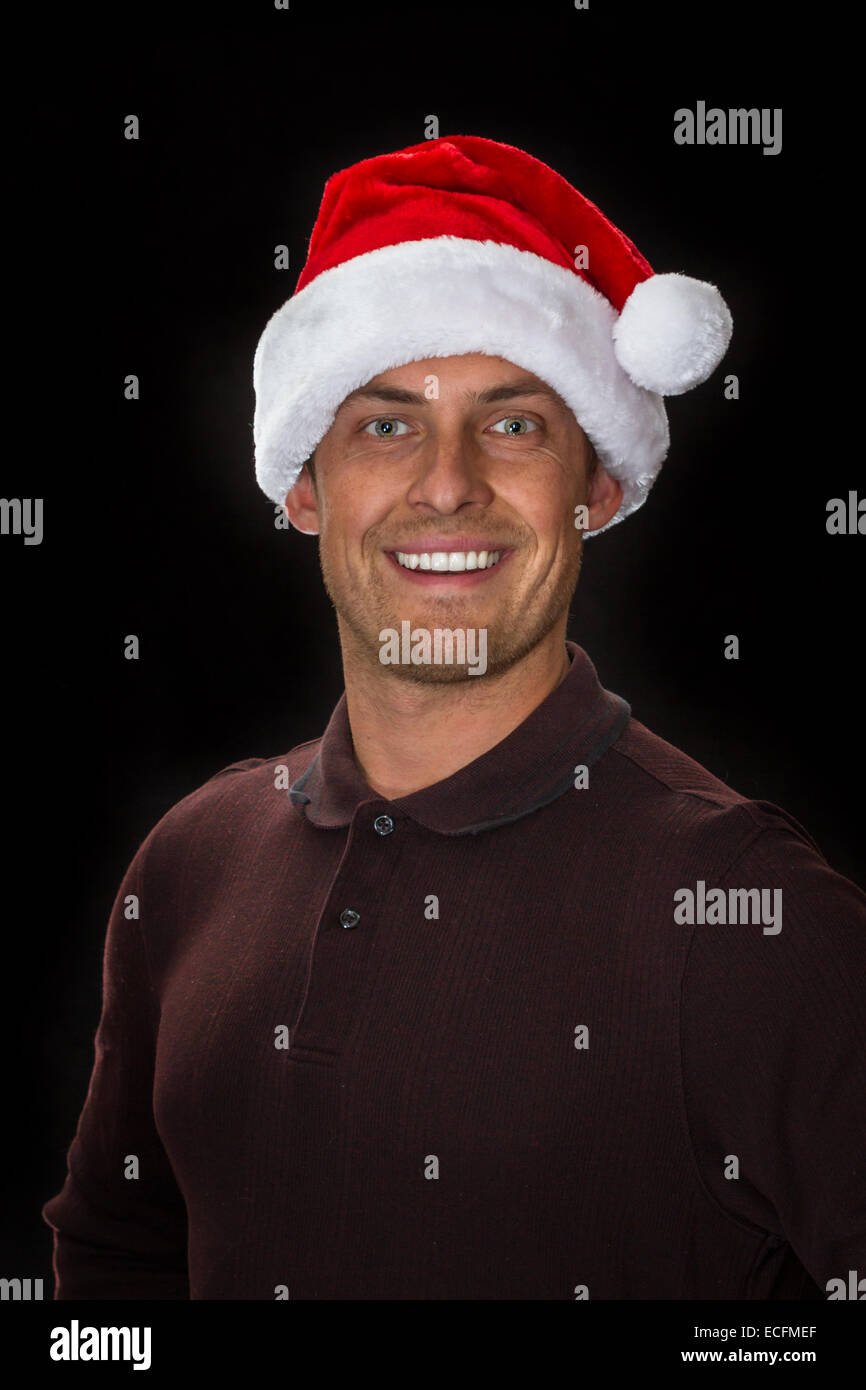 young smiling man wearing a santa hat isolated on a black background ...