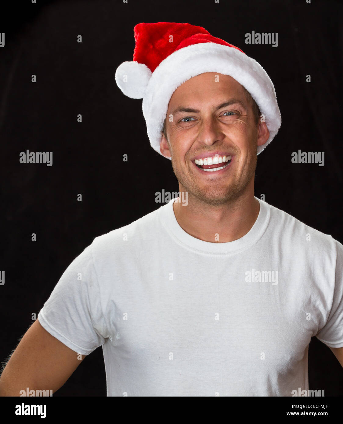 young smiling man wearing a santa hat isolated on a black background ...