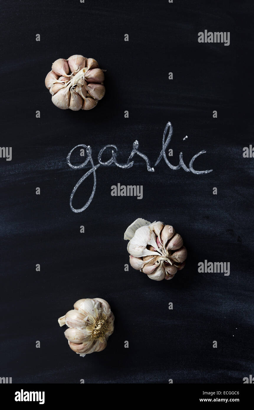 Cloves of garlic over black chalkboard with handwritten word "garlic ...