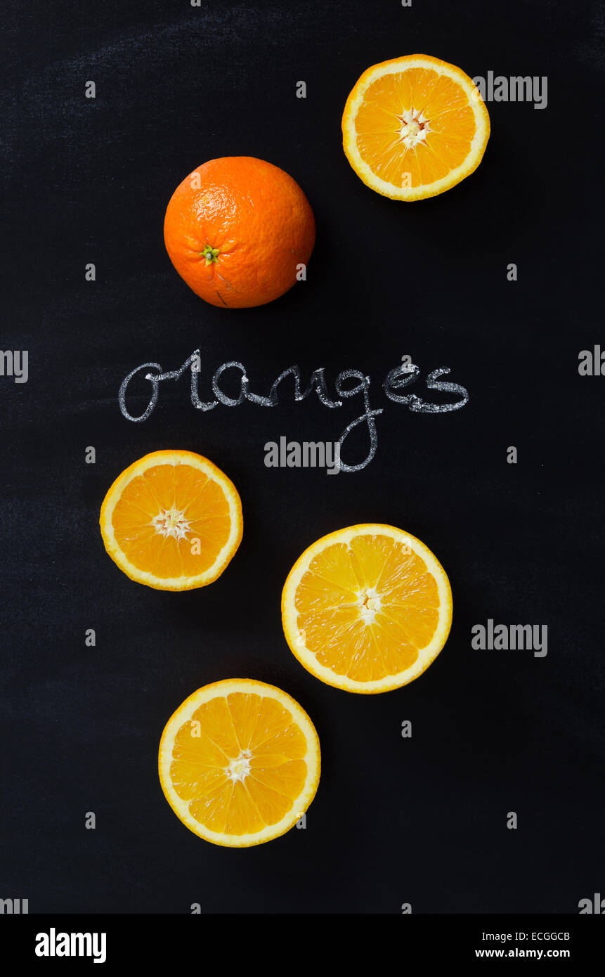 Orange fruits over black chalkboard with handwritten "oranges" word ...