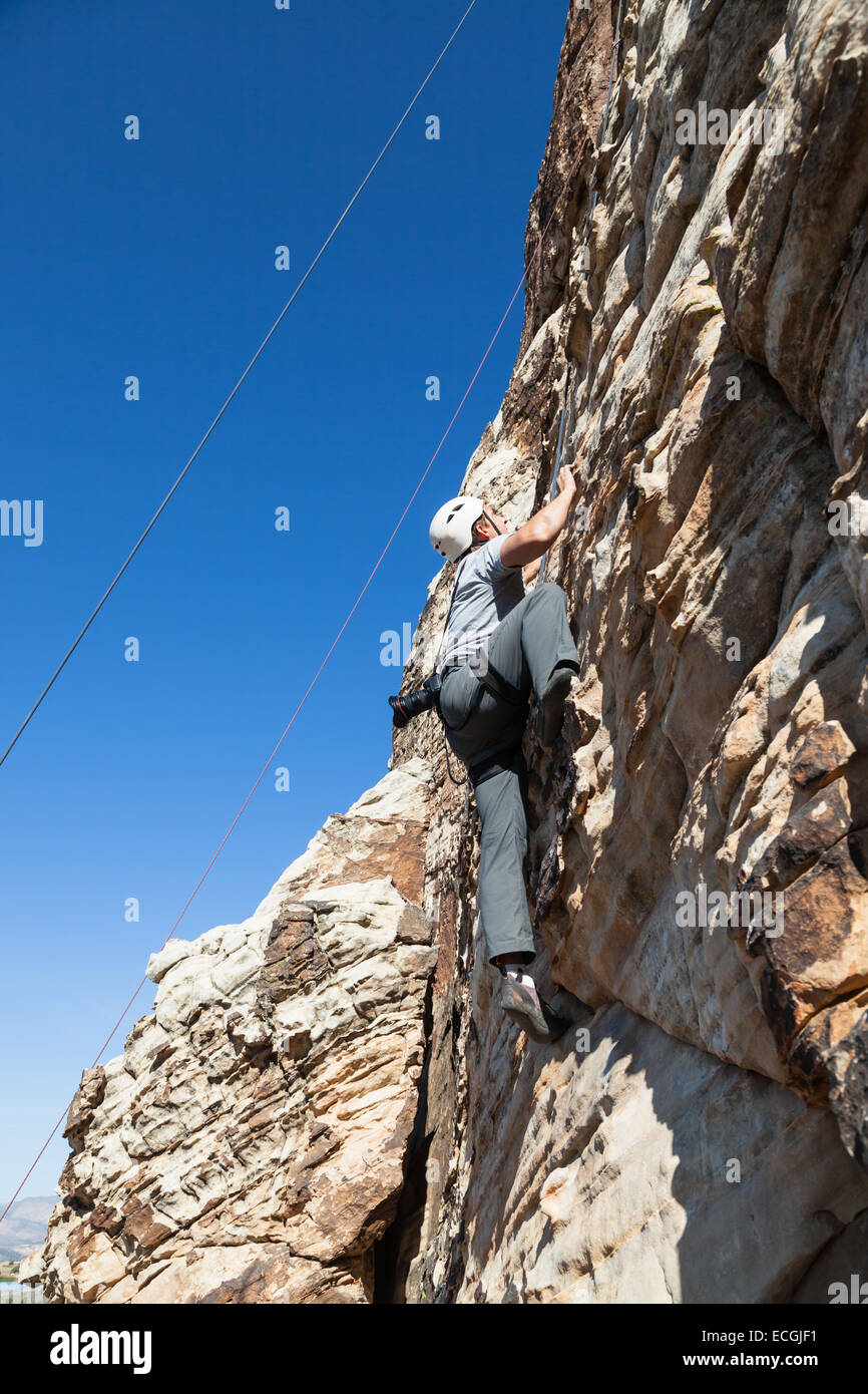 young man rock climbing for a first time wit a big smile and safety ...