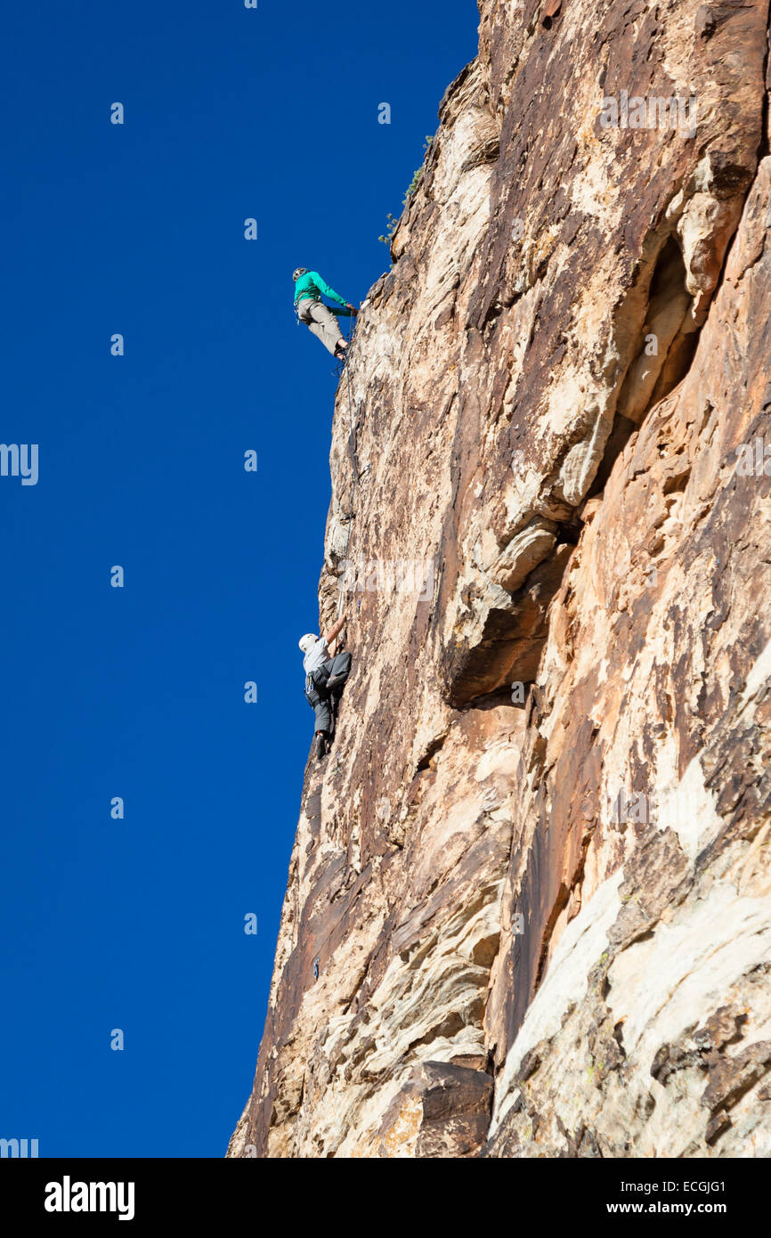 young man climbing a sandstone cliff with all the necessary safety gear ...