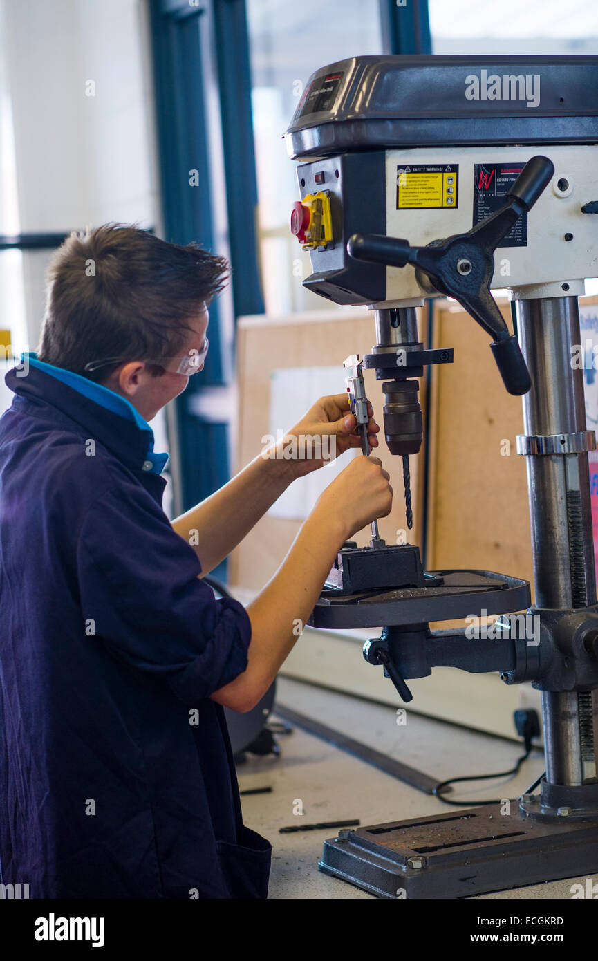 Secondary education, a teenage boy setting up a bench drill ...