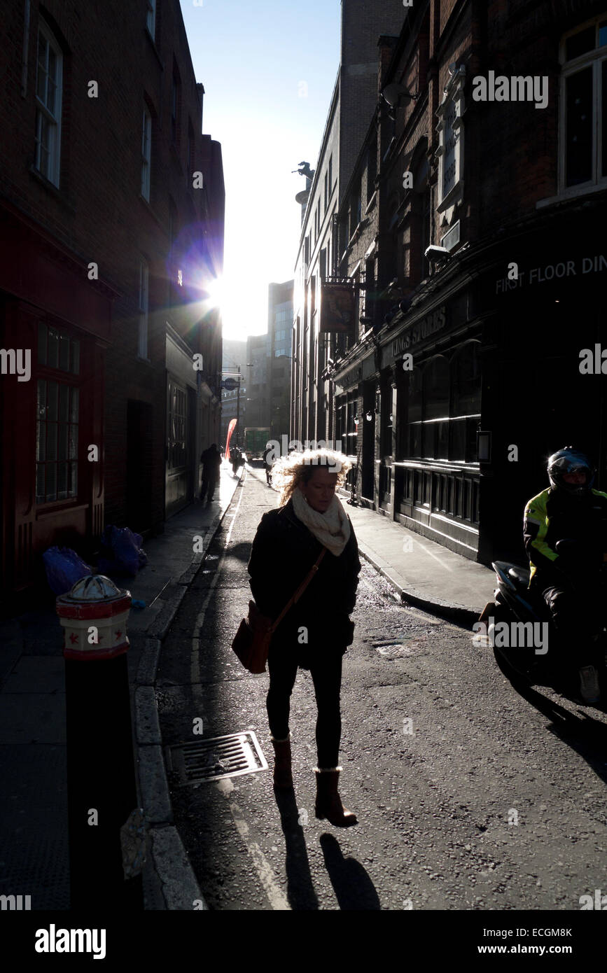 Woman walking in sunshine and shadows at the corner of Sandy's Row ...