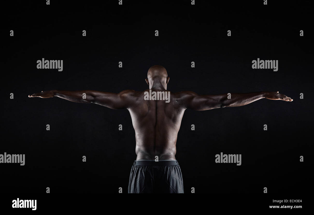 Portrait of a strong back of a African muscular man stretching his arms ...