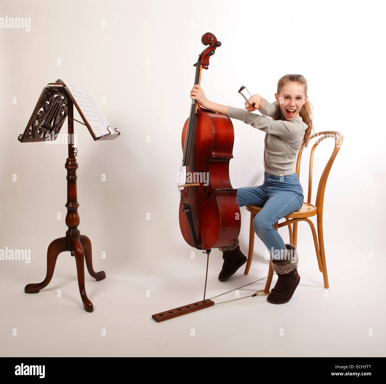 Happy young girl holding her Cello and smiling whilst pointing her bow ...