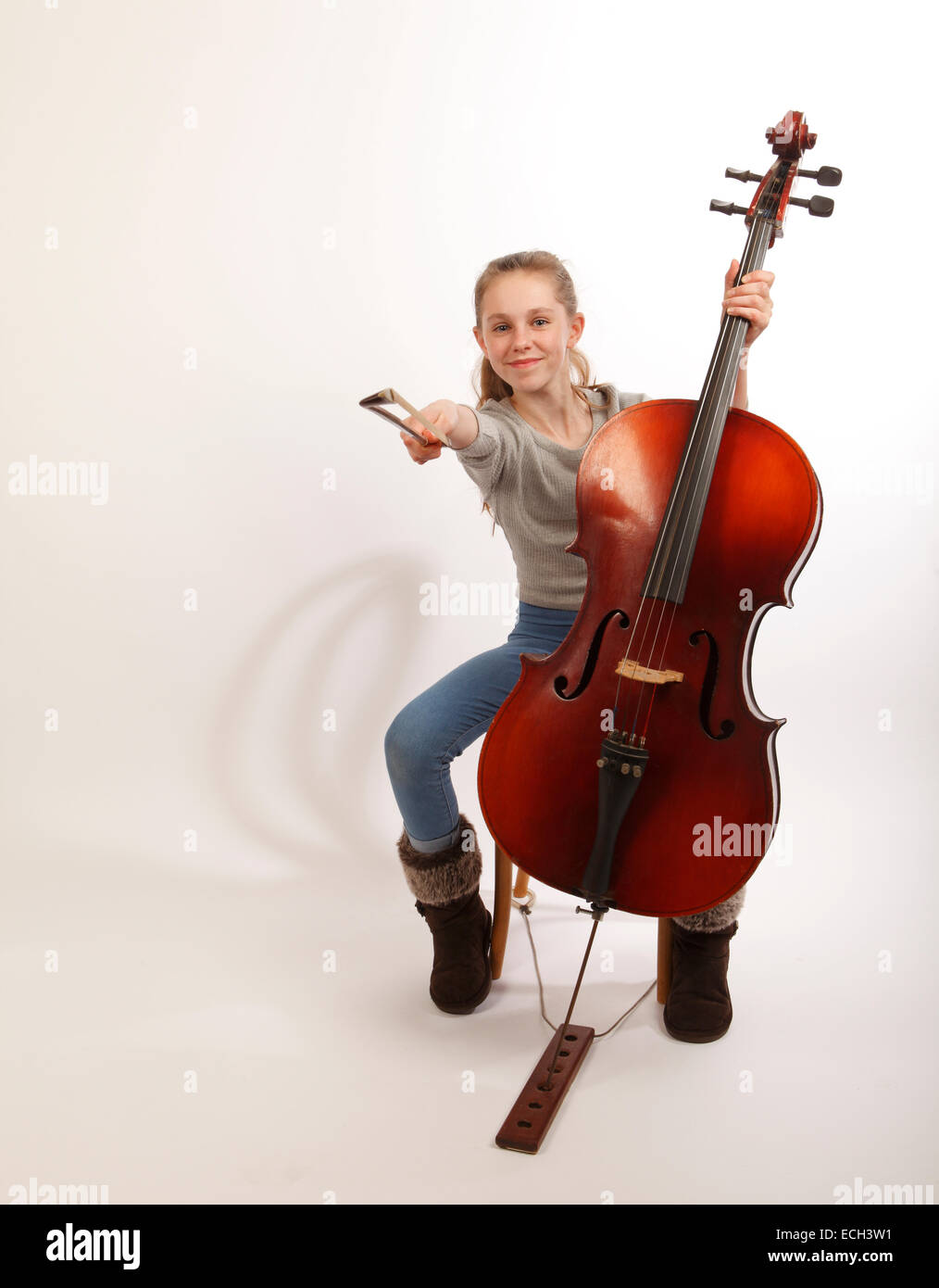 Happy young girl holding her Cello and smiling whilst pointing her bow ...