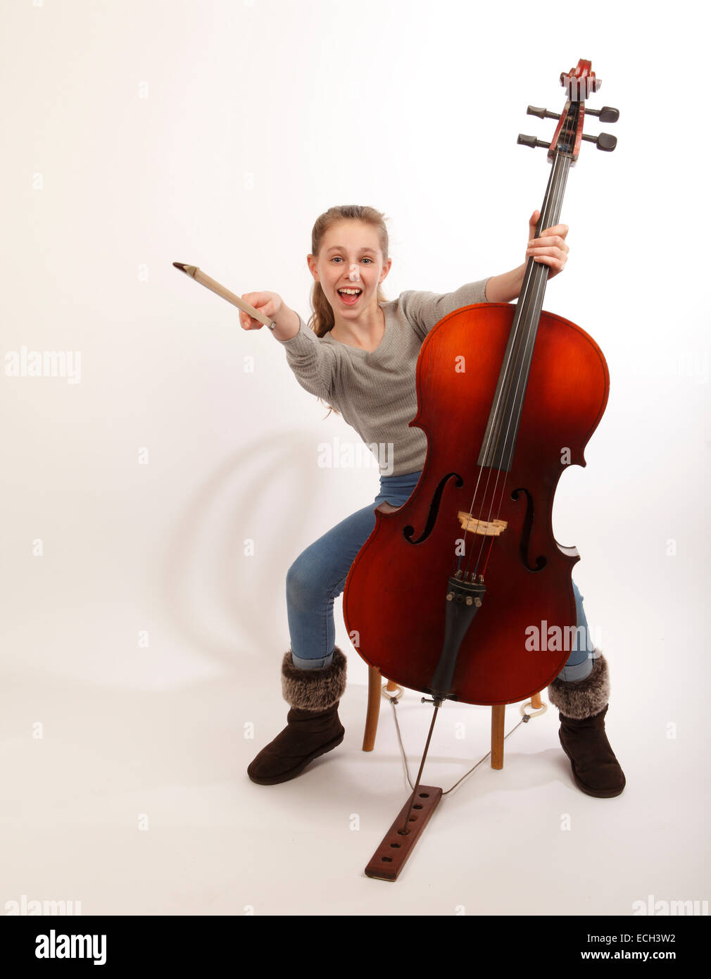 Happy young girl holding her Cello and smiling whilst pointing her bow ...