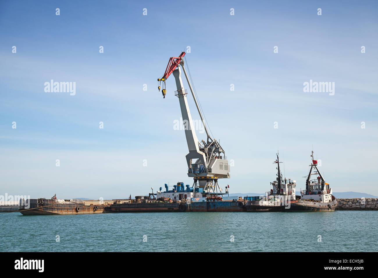 Floating crane and tug boats stand moored in the port of Tangier ...