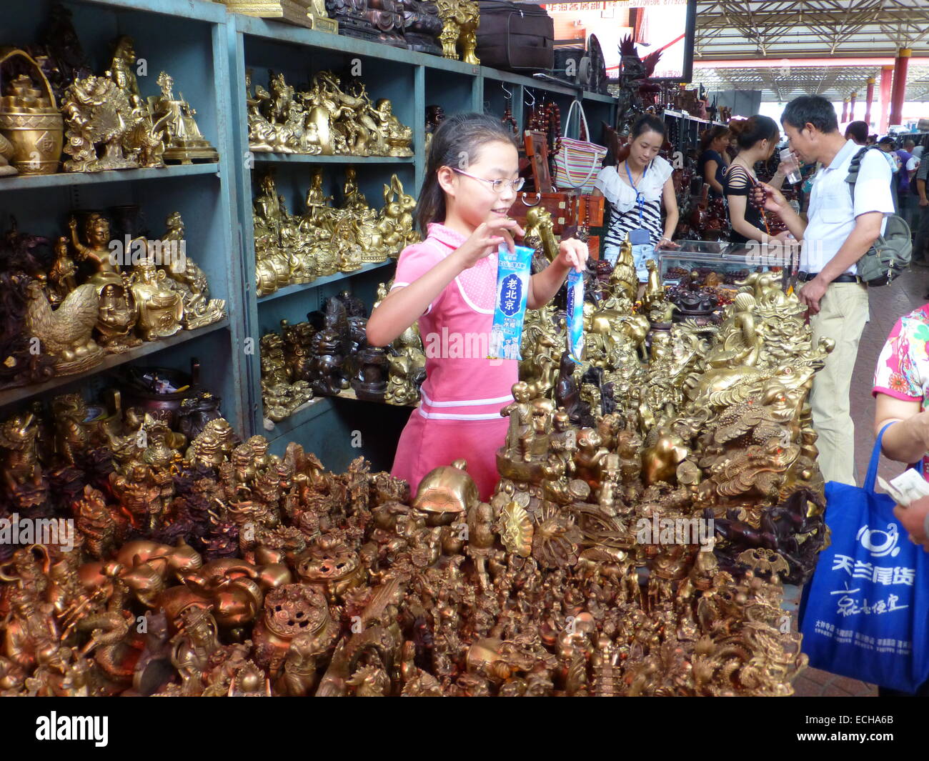 outdoor market place in China young girl selling brass and metal ...
