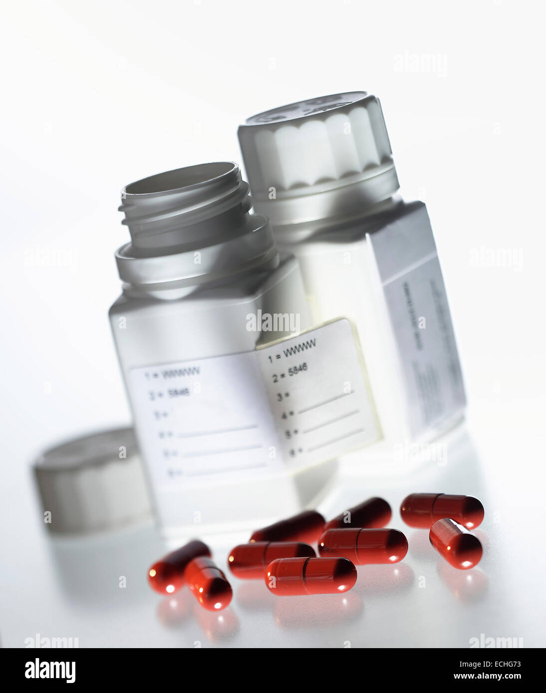 Two white plastic pill bottles with red capsules Stock Photo - Alamy