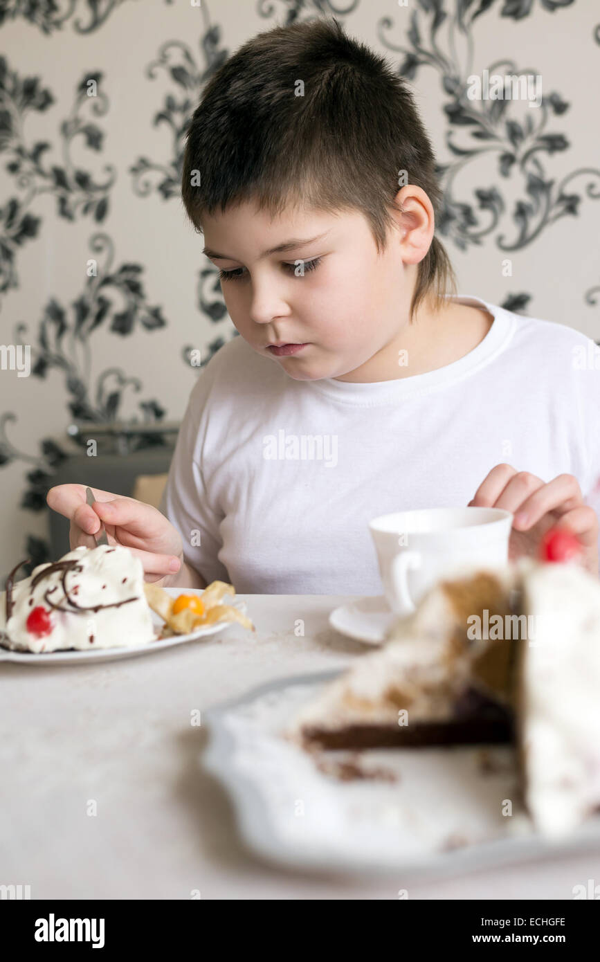Boy drinks tea with cake at table Stock Photo - Alamy