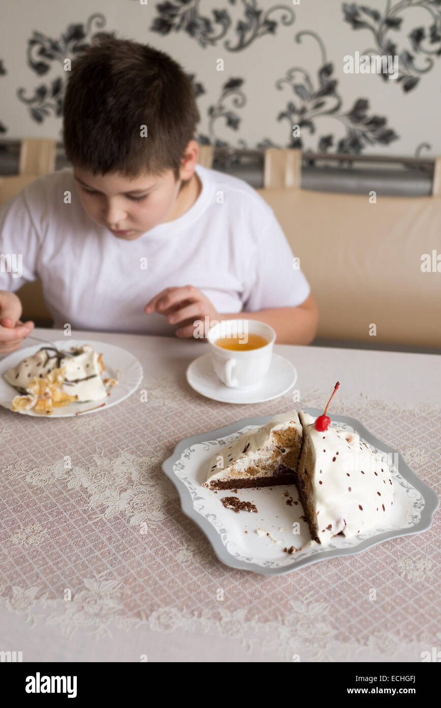 Boy drinks tea with cake at table Stock Photo - Alamy
