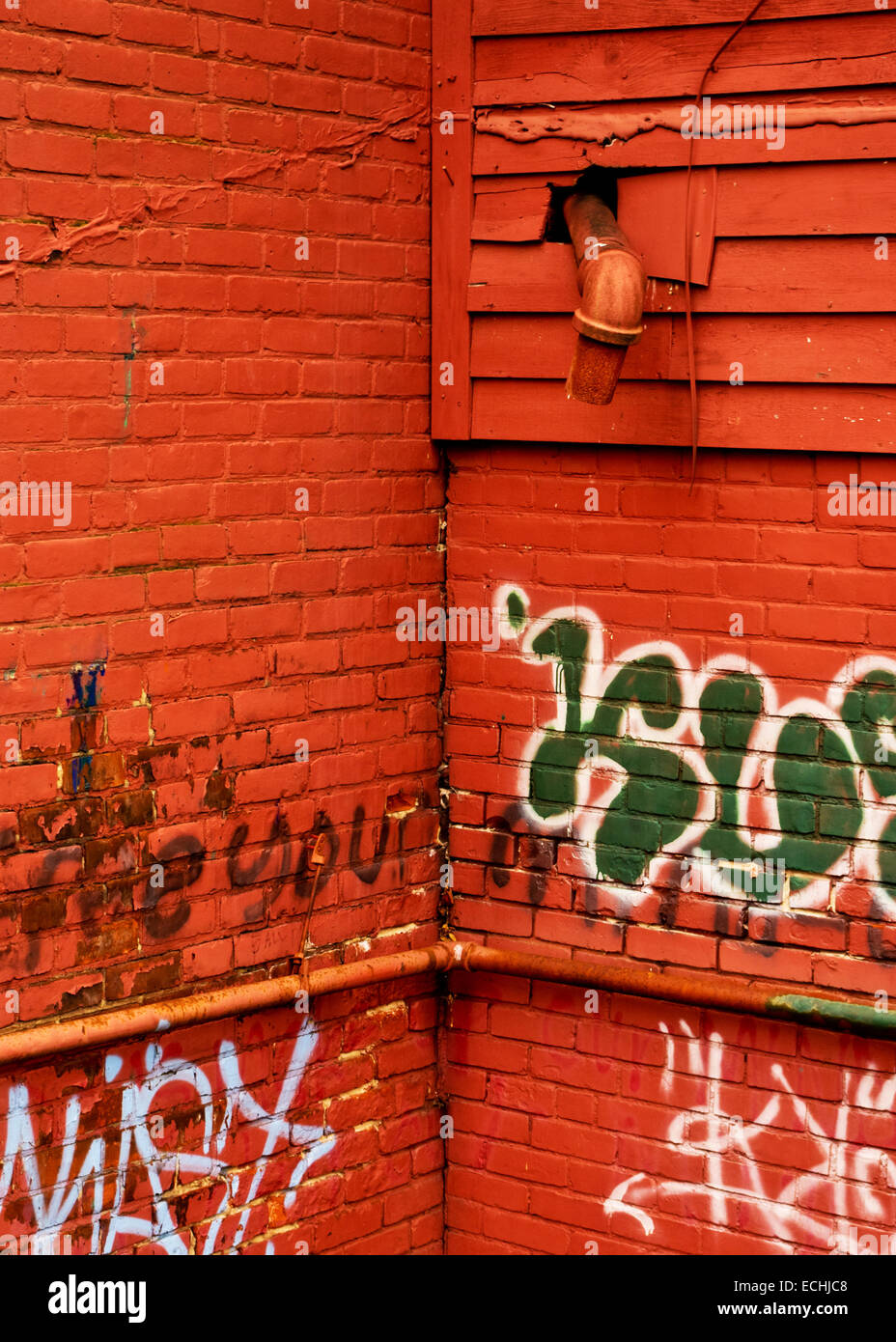 Graffiti, pipes and wires against a red-orange brick wall Stock Photo ...