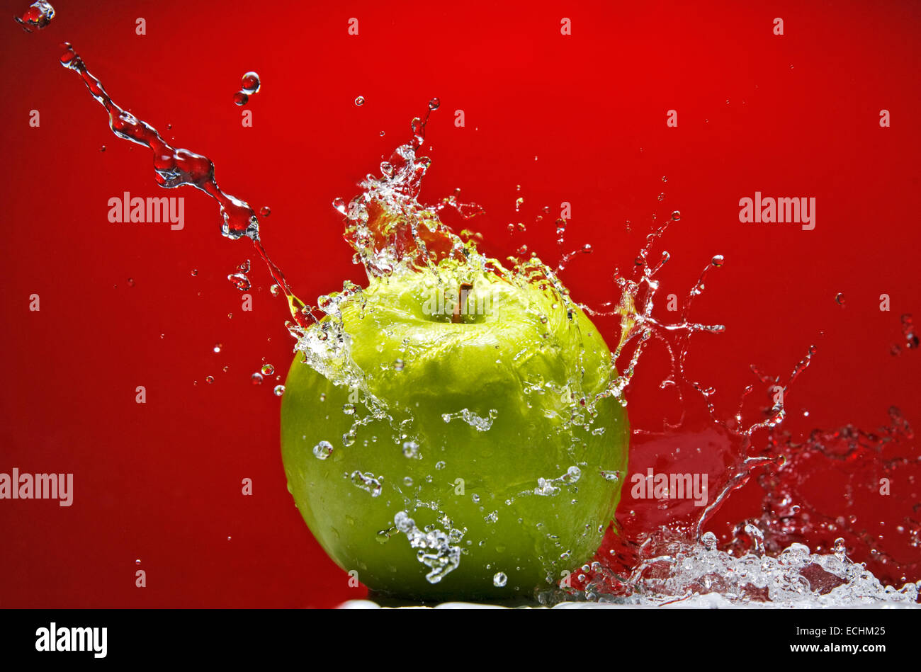Green apple with water splash on red background Stock Photo - Alamy