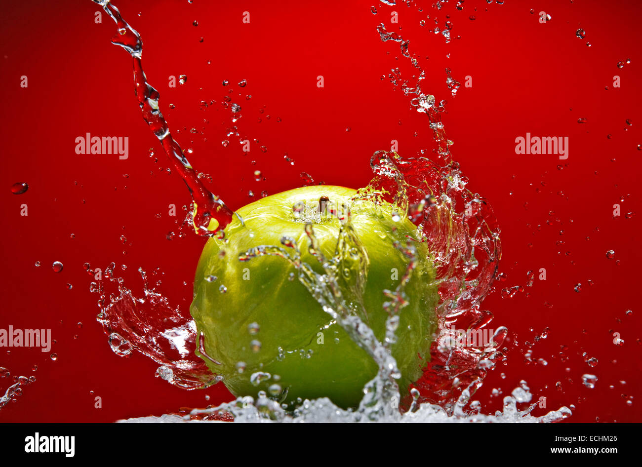 Green apple with water splash on red background Stock Photo - Alamy