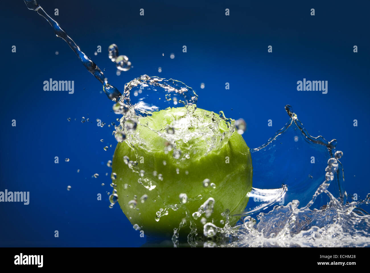 Green apple with water splash on blue background Stock Photo - Alamy