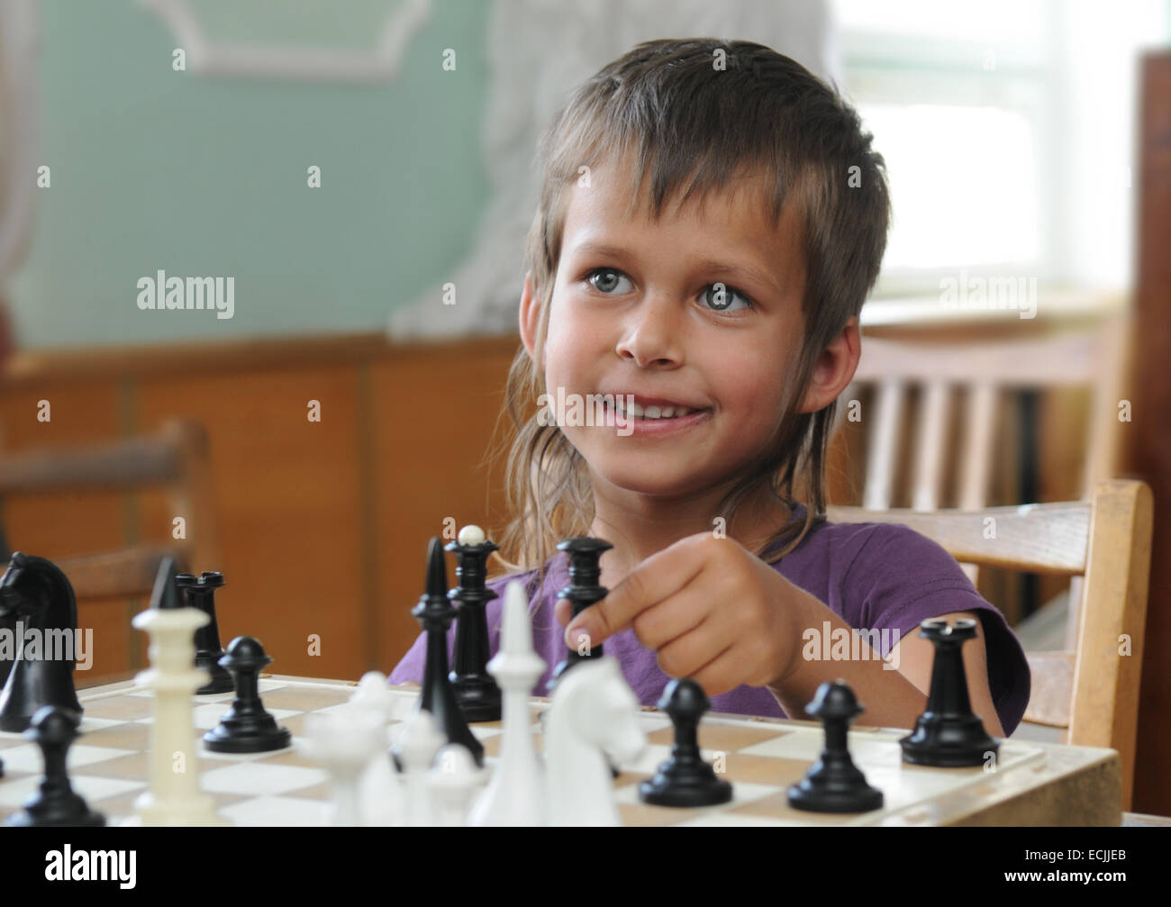 Little girl is playing chess. She is smiling Stock Photo - Alamy