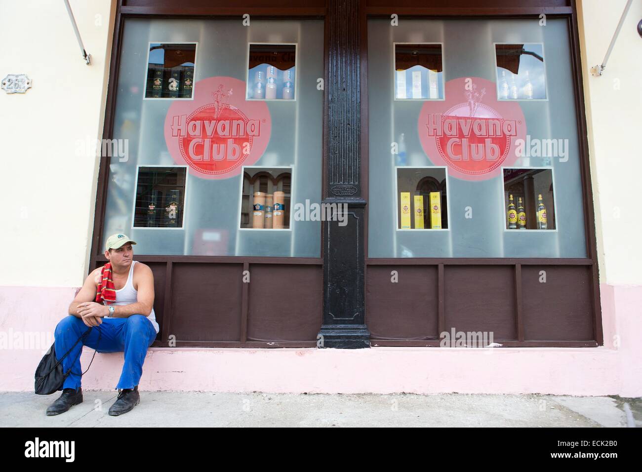 Cuba, La Habana, man sitting in front of the Havana Club shop window ...