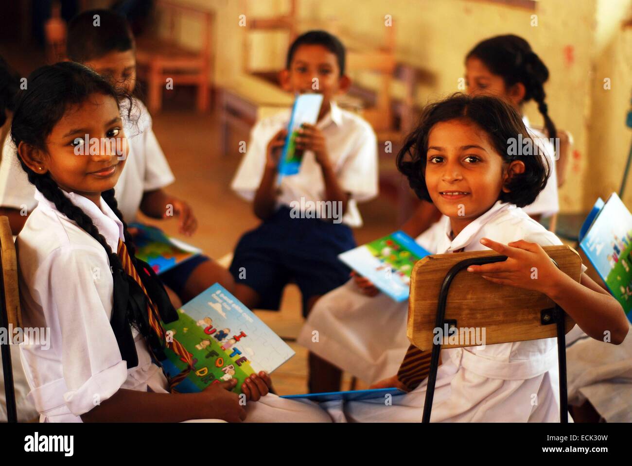 Sri Lanka, Colombo, children in uniform looking at Unicef children book ...