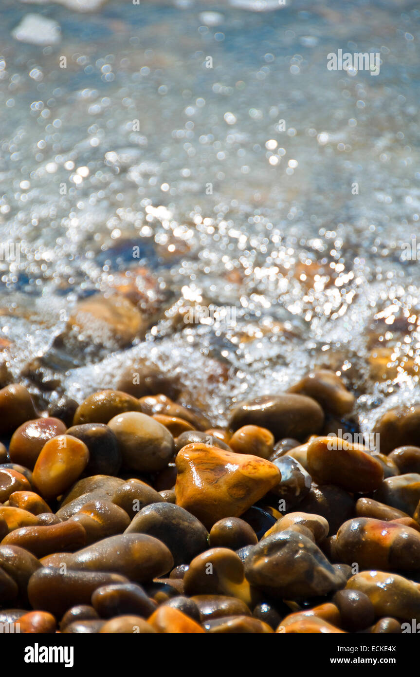 Vertical view of small colourful pebbles and the sea in the Isle of ...