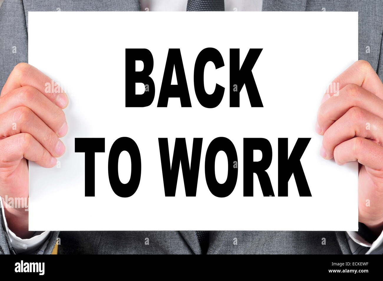 a man in suit holding a signboard with the sentence back to work ...