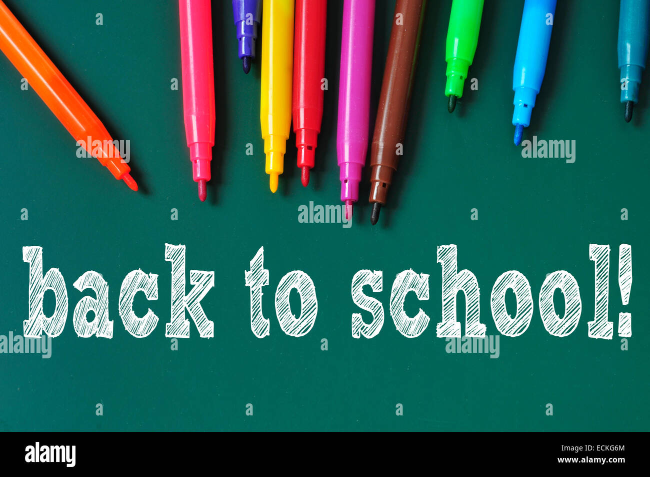 sentence back to school written in a green chalkboard and some felt-tip ...