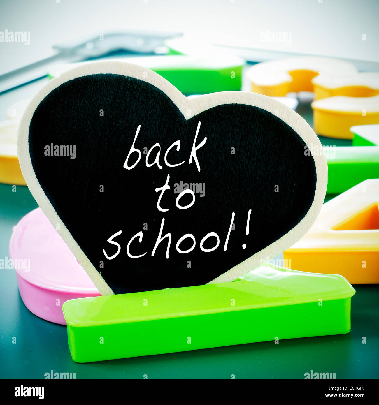 sentence back to school written in a heart-shaped blackboard and a pile ...