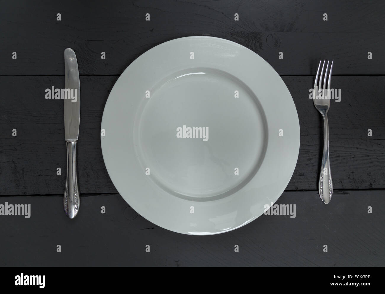 Cutlery and plate on a black wood background Stock Photo - Alamy