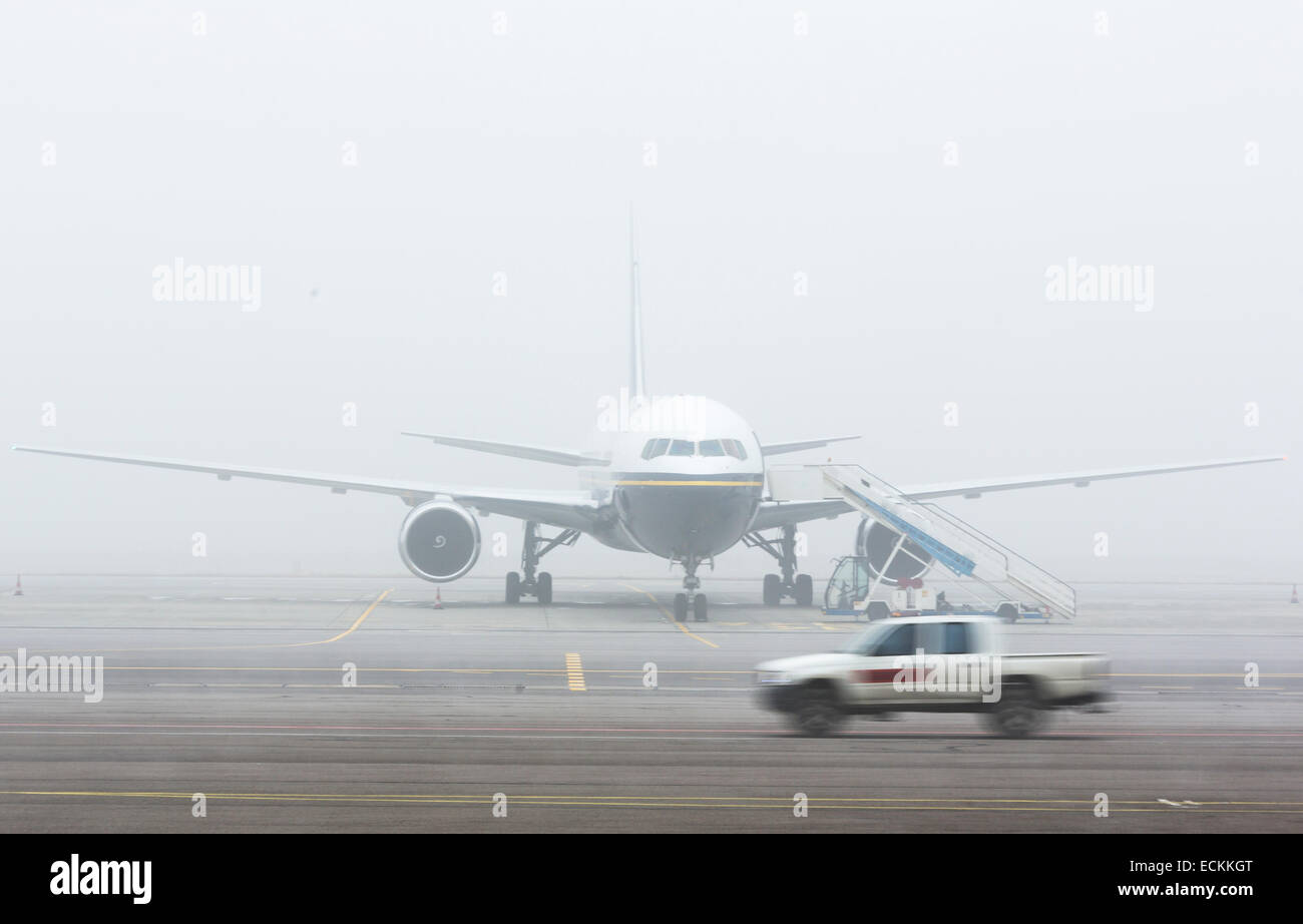 Airplane on the landing strip covered in mist and a car passing in ...