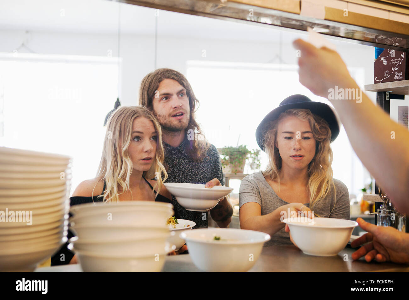 Friends taking food from counter at restaurant Stock Photo - Alamy