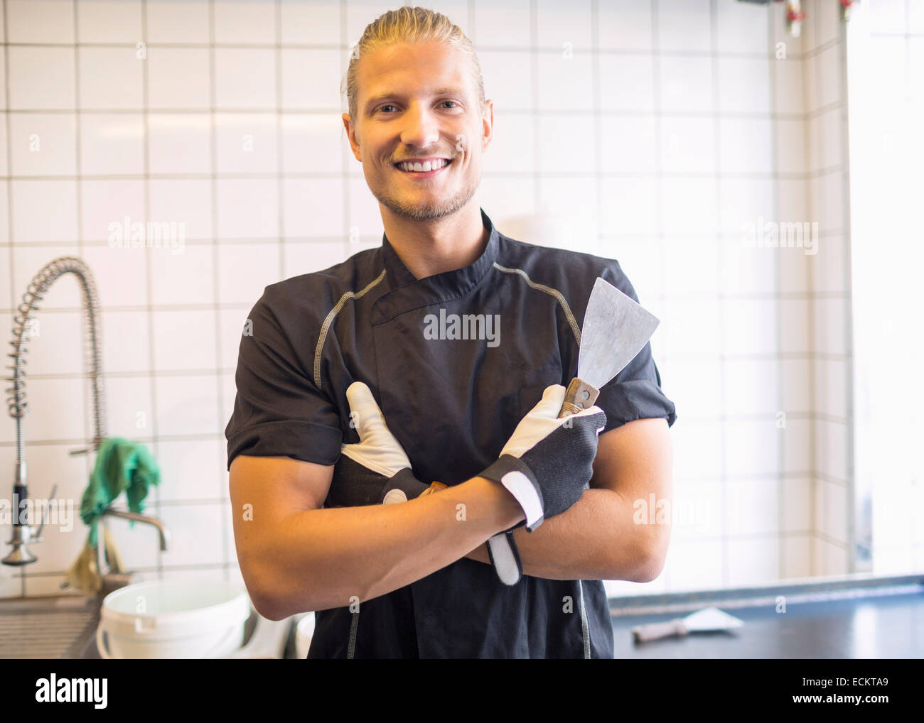 Portrait of smiling male worker with arms crossed standing in candy ...