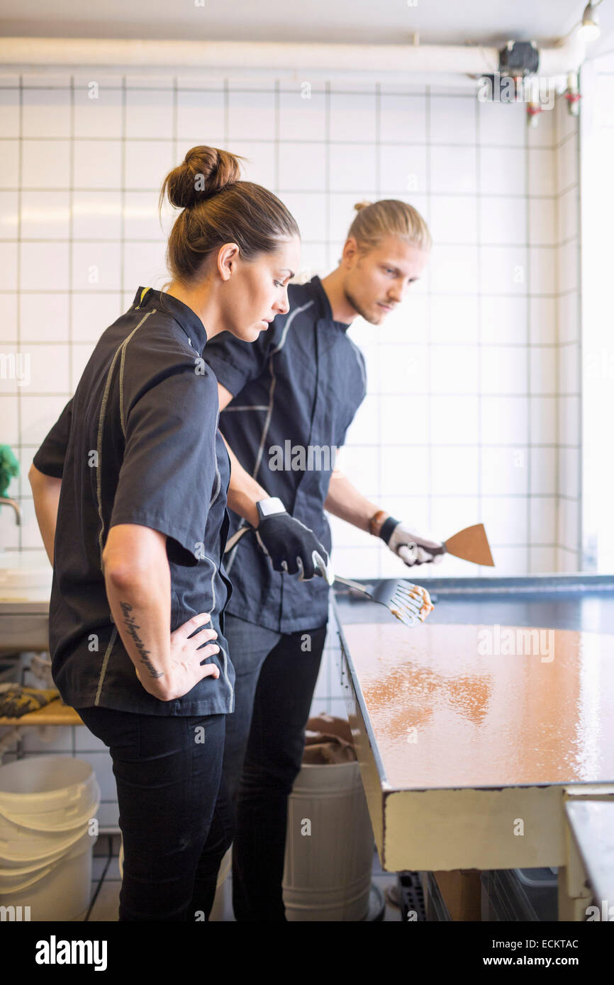 Workers looking at caramel in container at candy store Stock Photo - Alamy