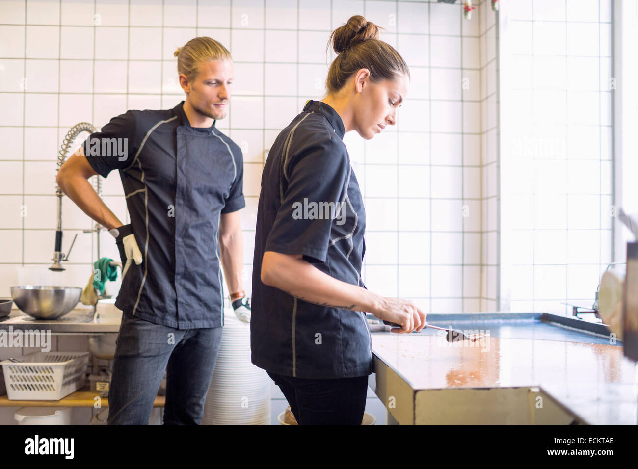 Male worker looking colleague making candies in store Stock Photo - Alamy