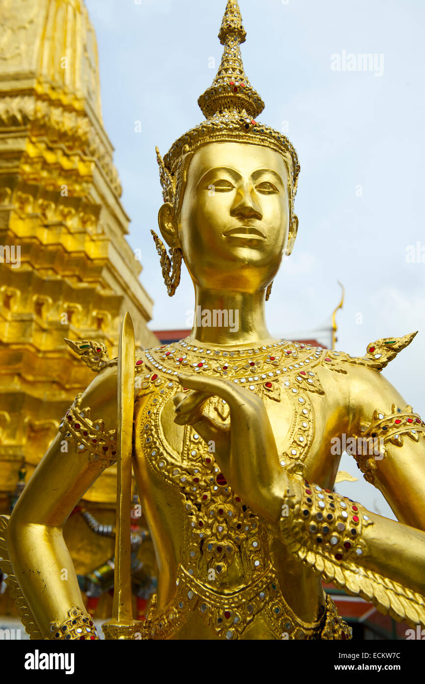 Golden kinnon (kinnaree) statue holding a rose with a golden phra chedi ...