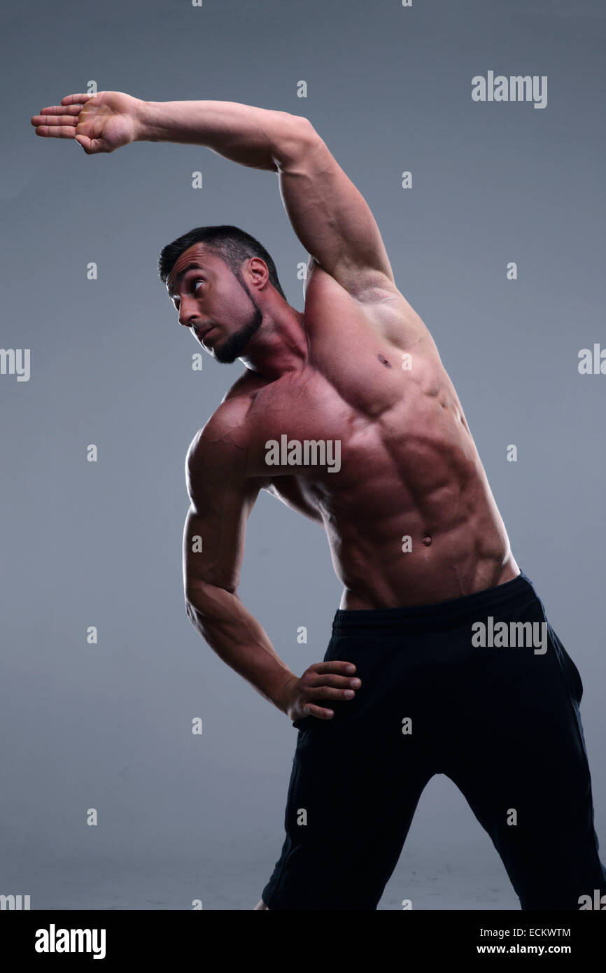 Young man stretching over gray background Stock Photo - Alamy