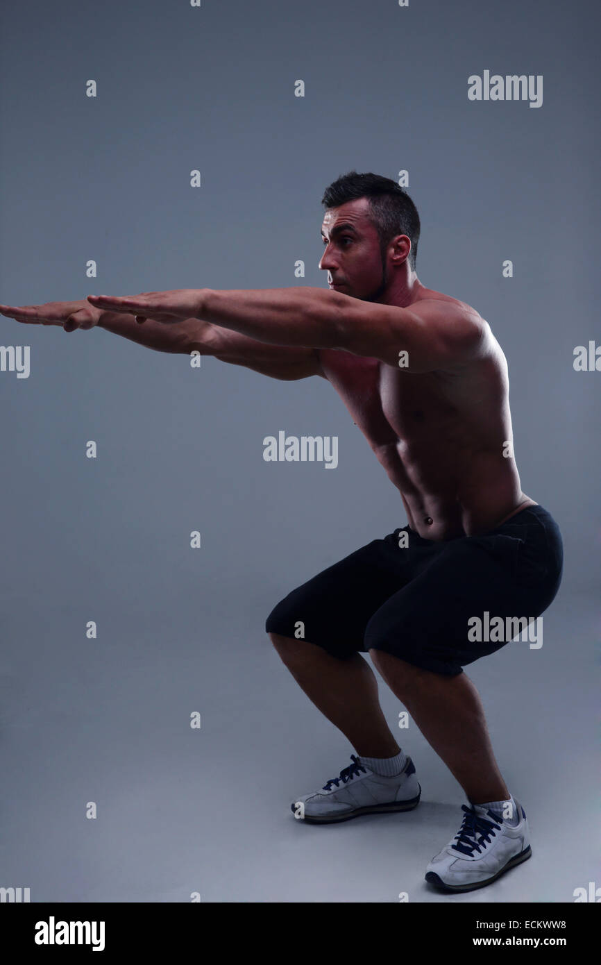 Athletic young muscular man doing squats Stock Photo - Alamy