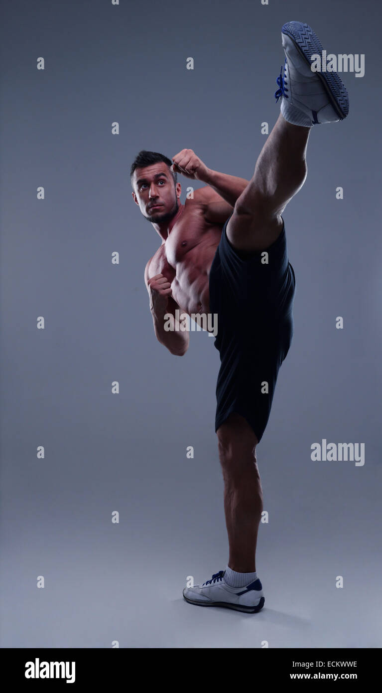 Portrait of a muscular man practicing body combat over gray background ...