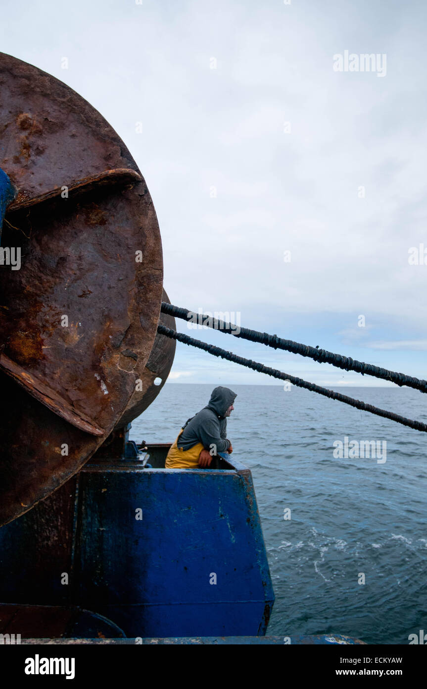 Fisherman works winch for the dragger net on fishing trawler ...