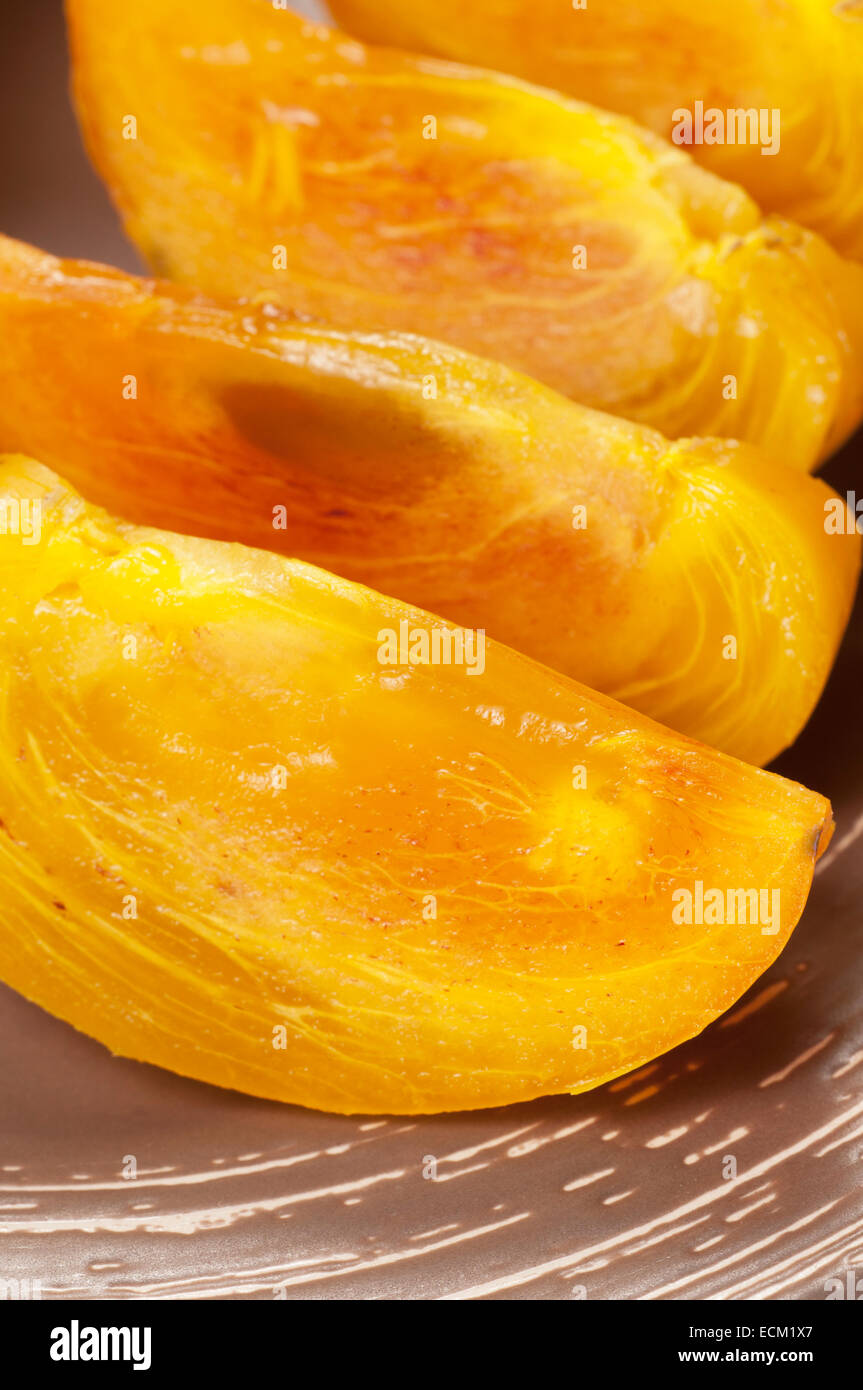 Persimmon fruit cuts on a ceramic plate, closeup Stock Photo - Alamy