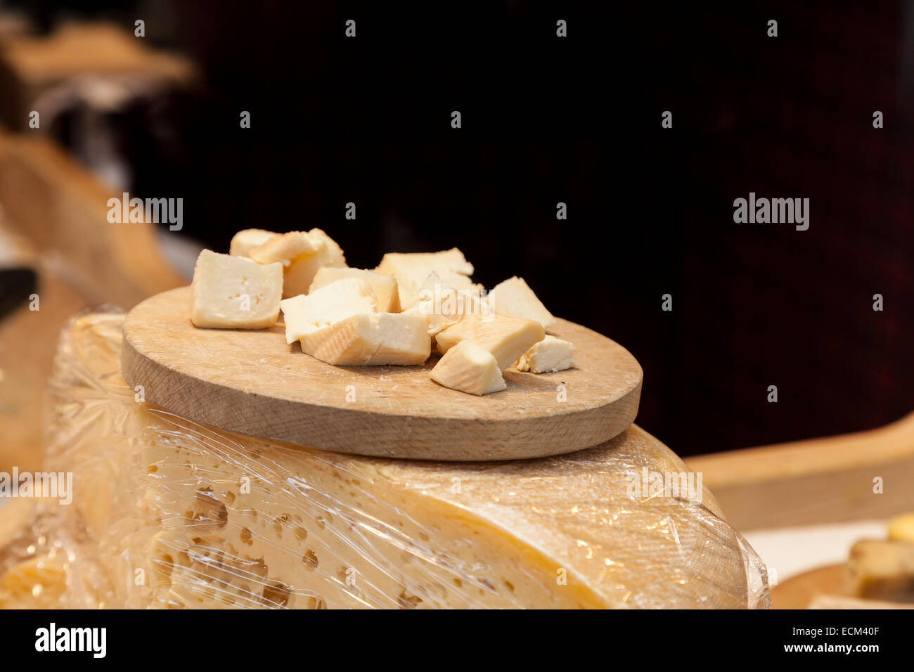 Close-up image of few small pieces of cheese on a wooden board in a ...