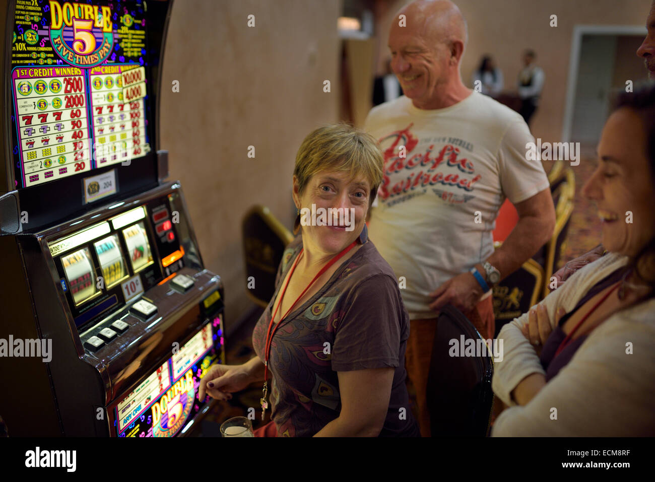 Group of friends laughing while watching smiling woman play a slot ...