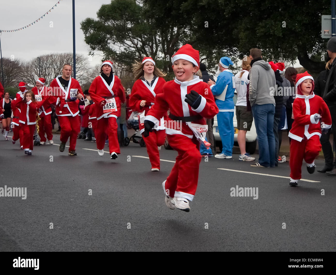 A young girl dressed as Santa Clause sticks her tongue out whilst ...