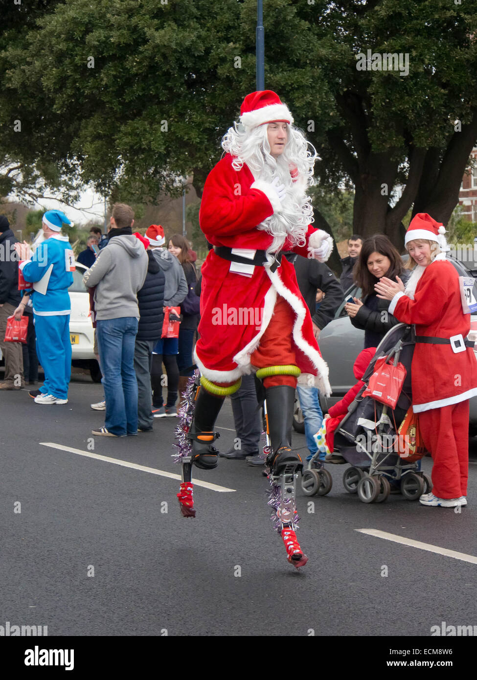 A man dressed as Santa Clause on mechanical leg extensions runs the ...