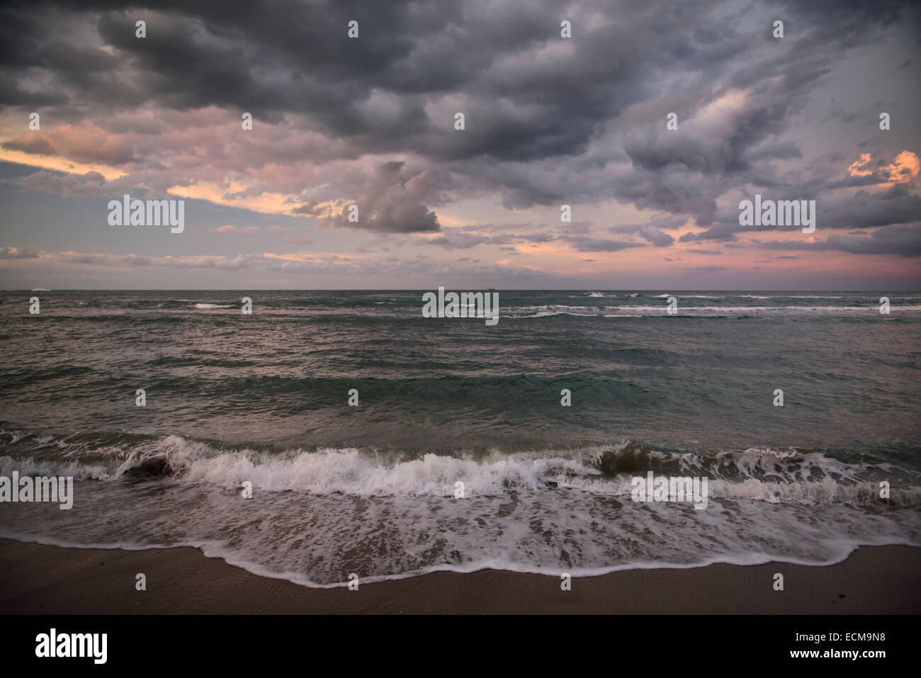 Dark pink clouds at sunset with coral reef waves on Atlantic Ocean ...