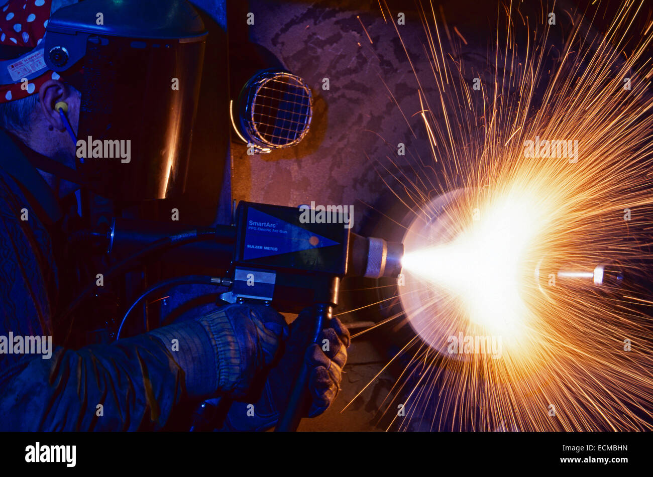 A worker welds with a an electric arc welder as he joins stainless ...